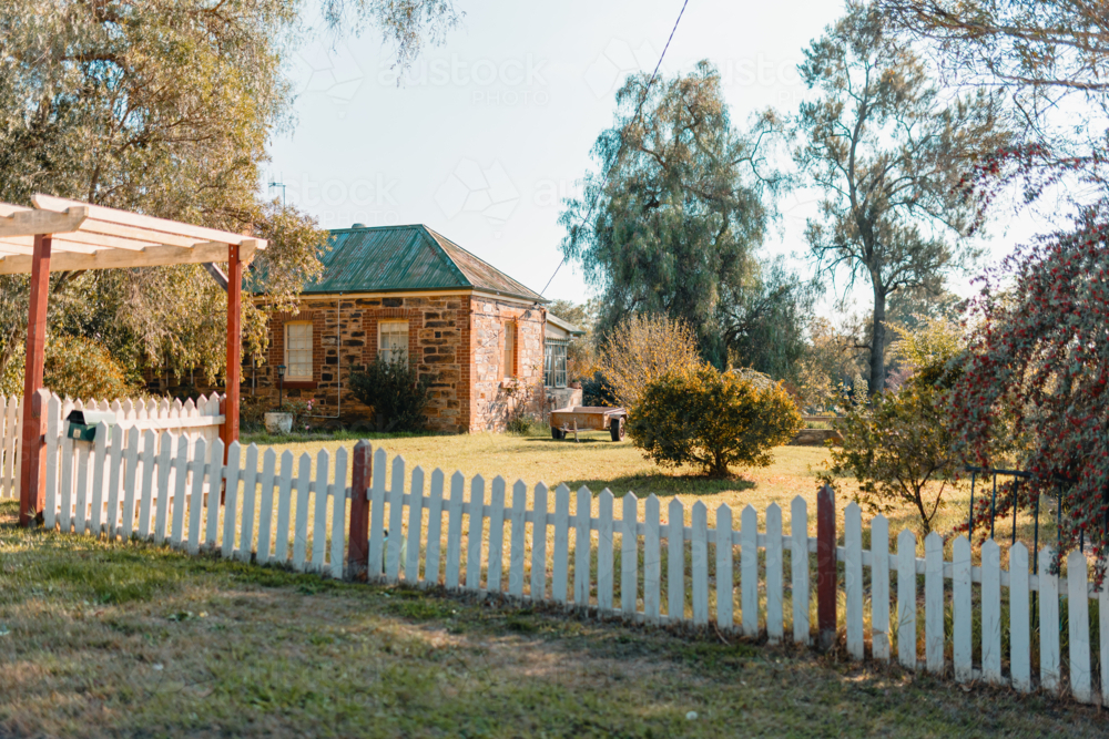 Image of Small stone cottage behind white picket fence in rural ...