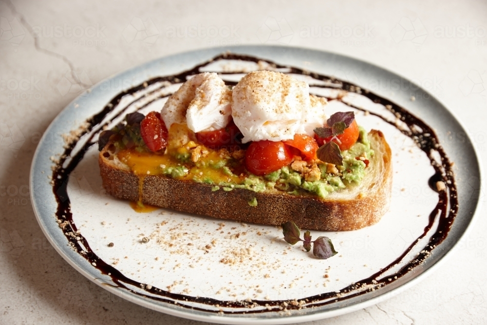 Image of smashed avocado toast with tomato and poached eggs - Austockphoto