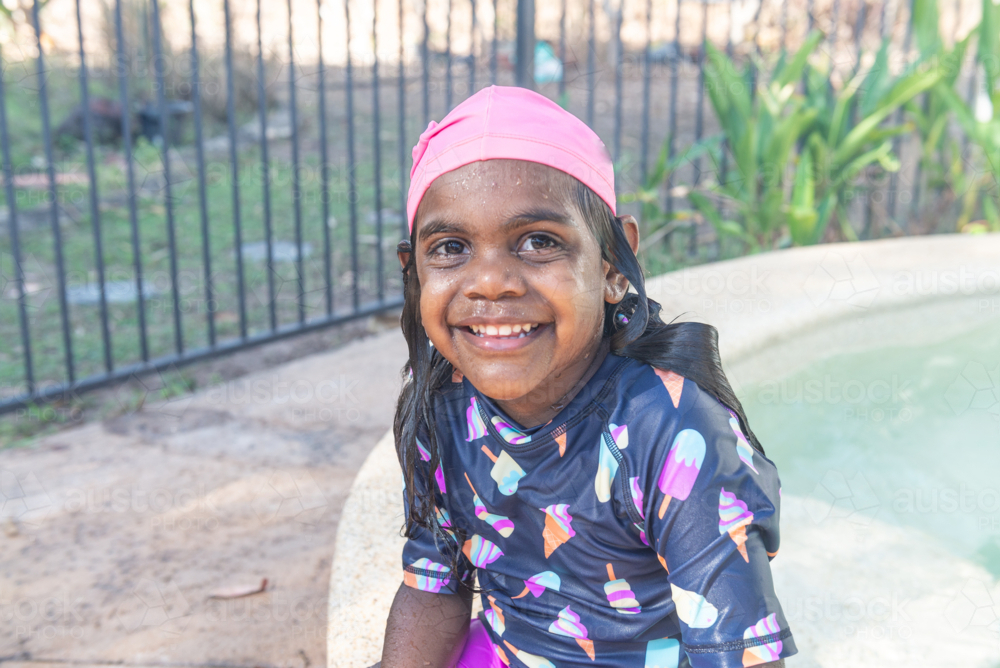 Image of Smiling aboriginal kid sitting by the pool - Austockphoto