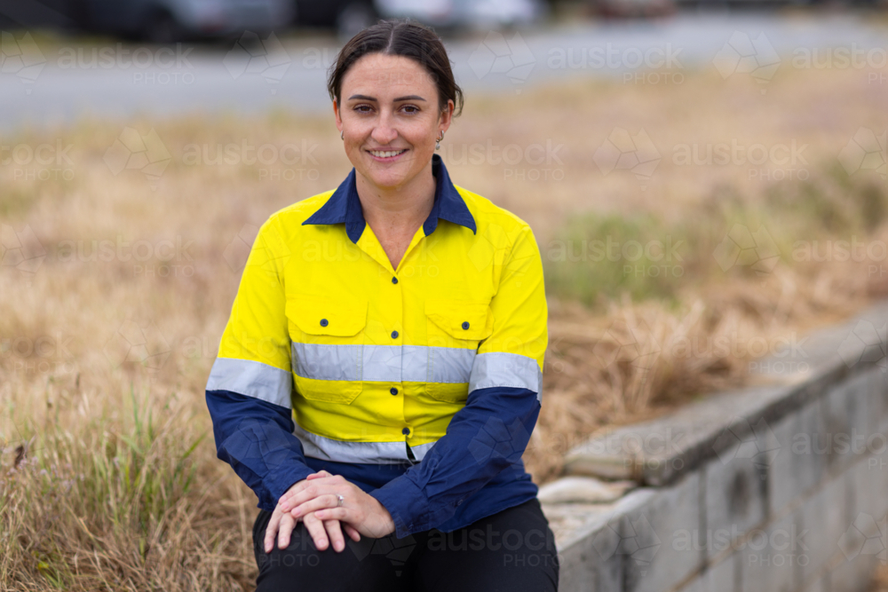 Image of smiling adult woman sitting on a concrete surface wearing a ...