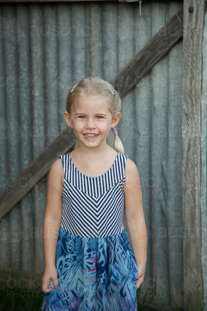 Image of Smiling little girl standing near shed door in portrait on ...