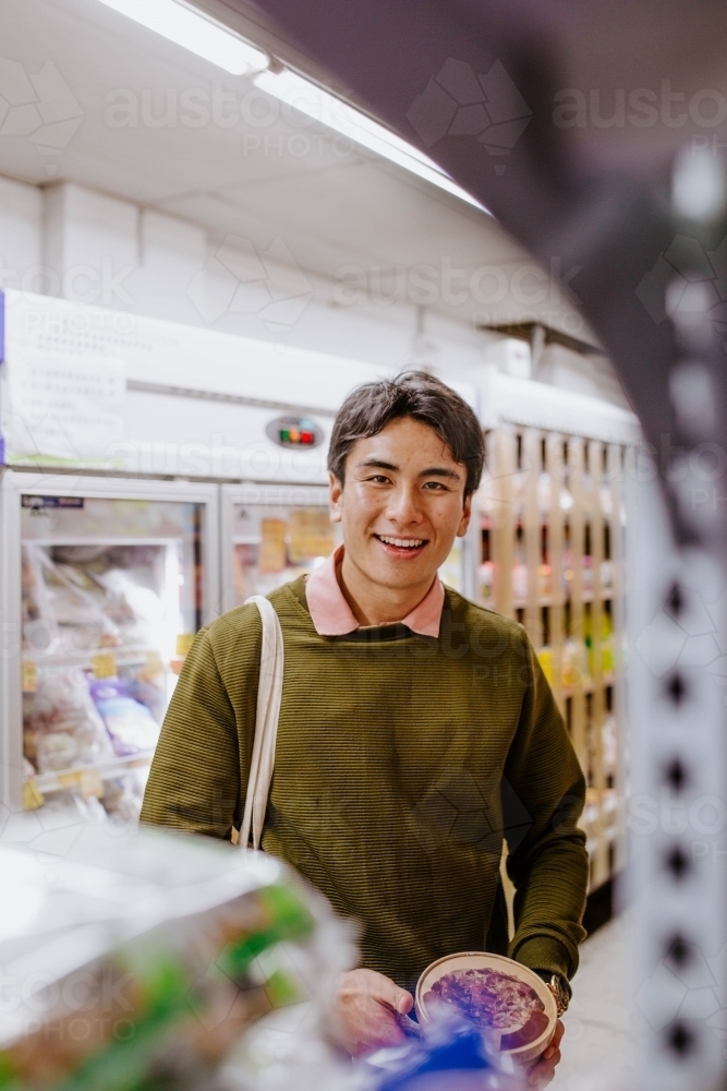 Image of Smiling man buying food from supermarket - Austockphoto
