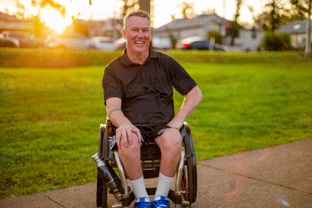 Image of Smiling man in wheelchair sits comfortably on path in park ...