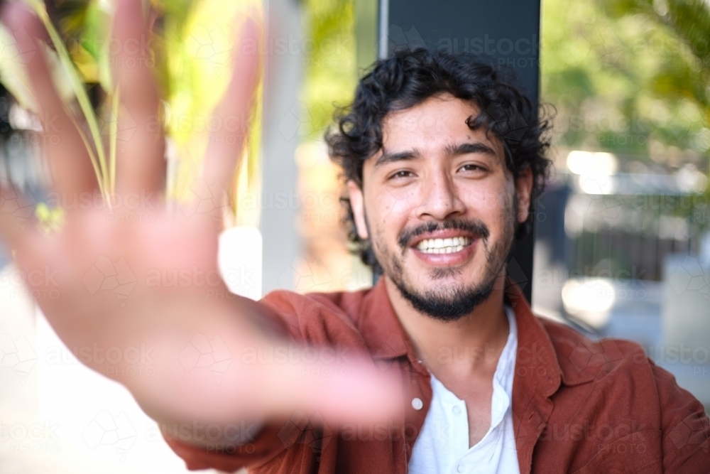 Image of Smiling man reaching toward the camera outside - Austockphoto
