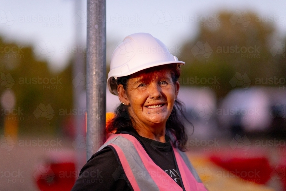 Image of smiling mature woman outside wearing hi-vis vest and a hard ...