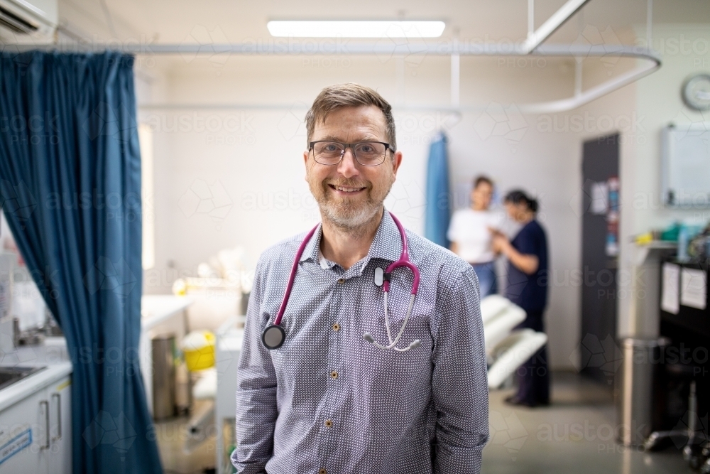 Image of Smiling middle-aged male doctor with a stethoscope around his ...