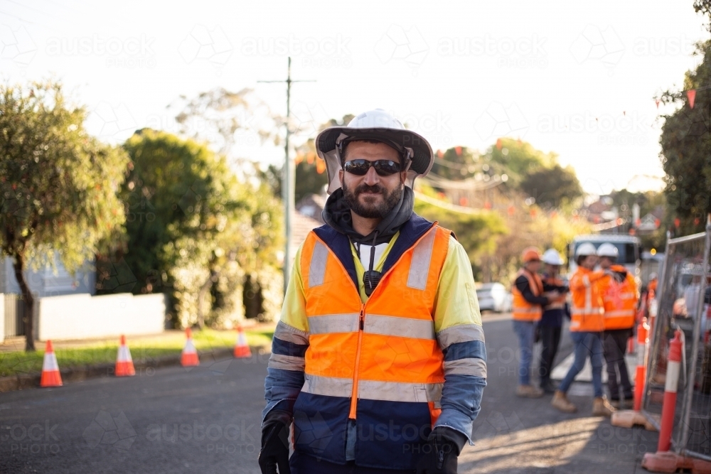 Image of Smiling road worker with beard wearing sunglasses, white hard ...
