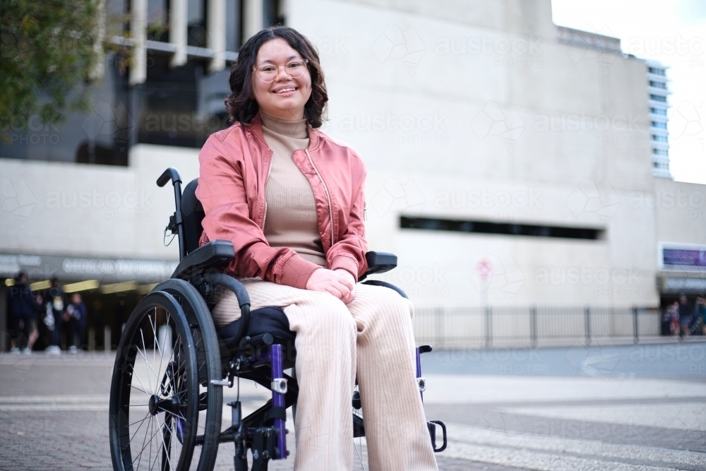 Image of Smiling woman in pink with a disability sitting in a ...