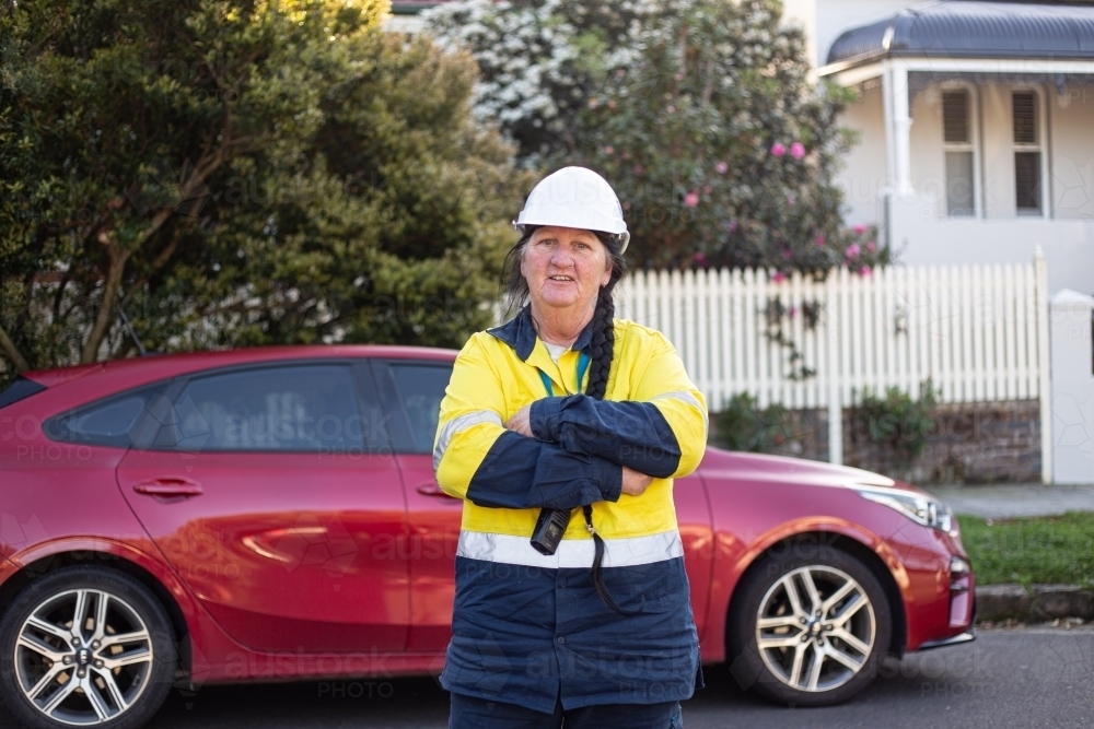 Image of Smiling woman road worker crossing her arms in front of a red ...