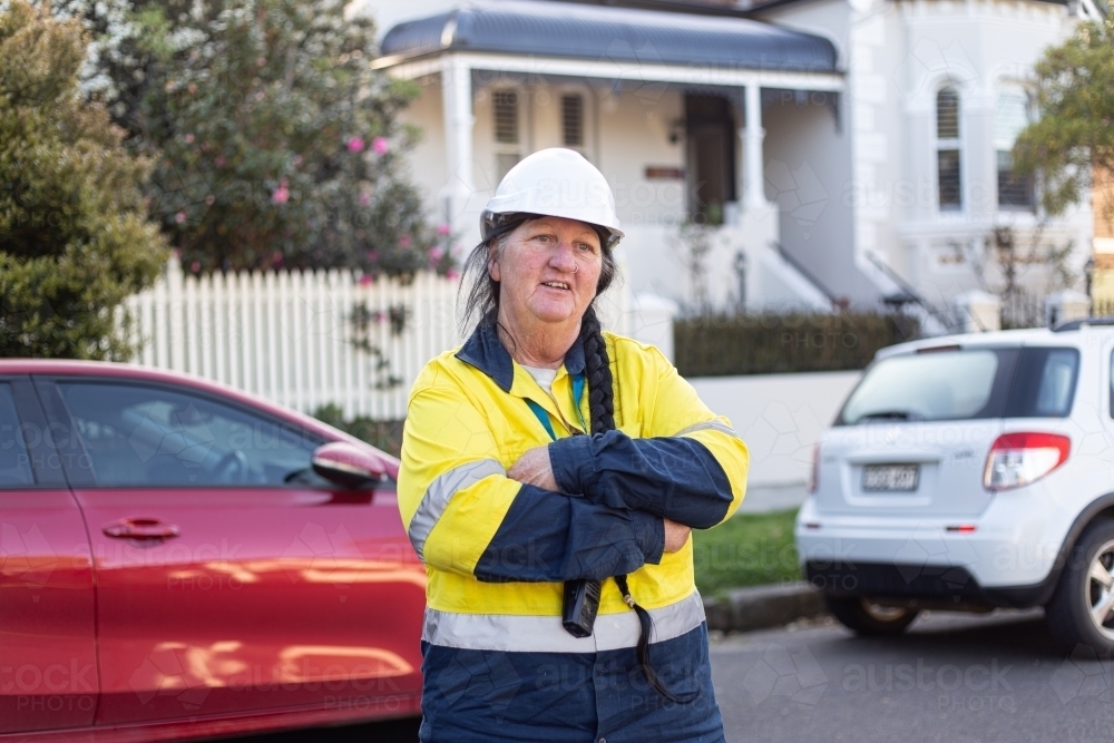 Image of smiling woman road worker crossing her arms in front of a red ...