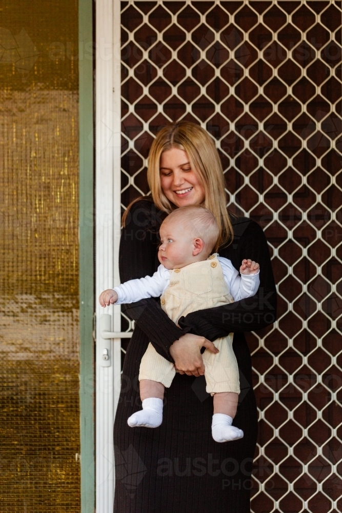 Image of smiling young aboriginal australian mum by front door of home ...