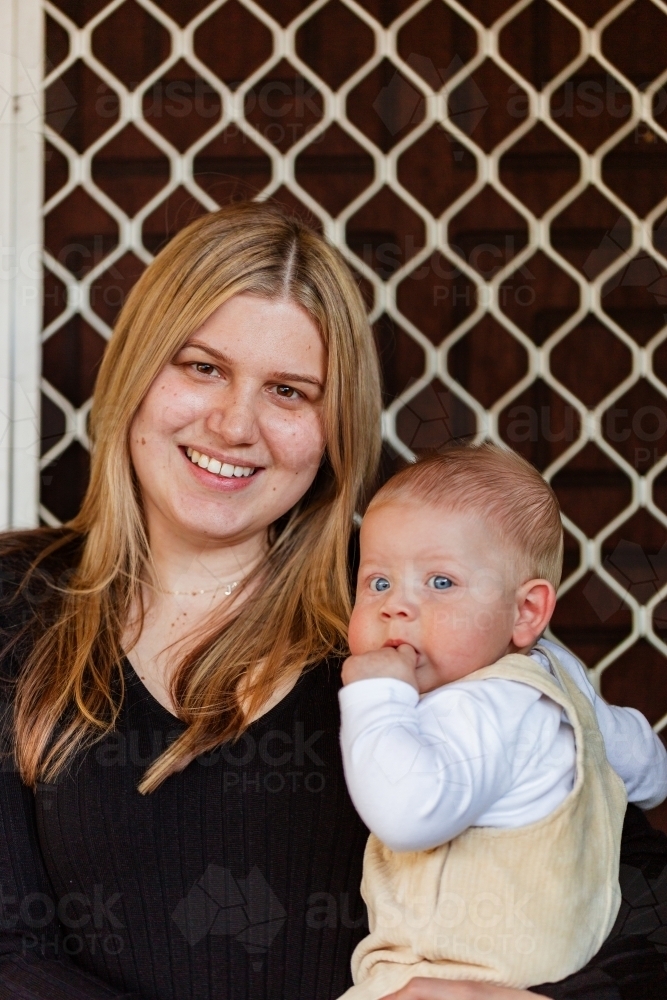 Image of smiling young aboriginal australian mum by front door of home ...