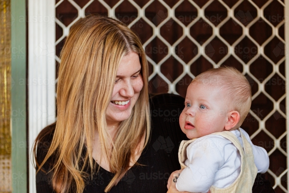 Image of smiling young aboriginal australian mum by front door of home ...
