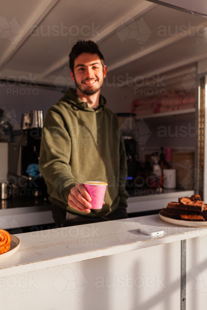 Image of smiling young Aussie barista man handing customer cup from ...