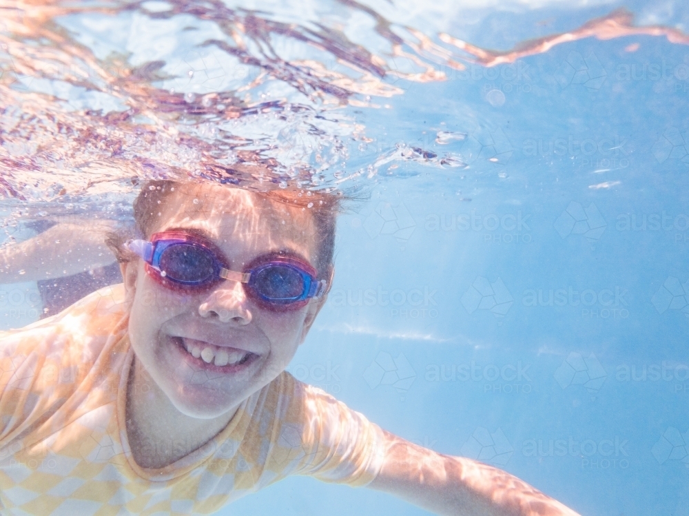 Image of Smiling young Australian girl swimming in pool with goggles on ...