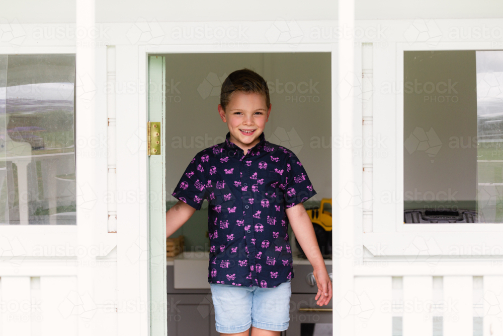 Image of Smiling young boy playing alone in cubby house standing in ...