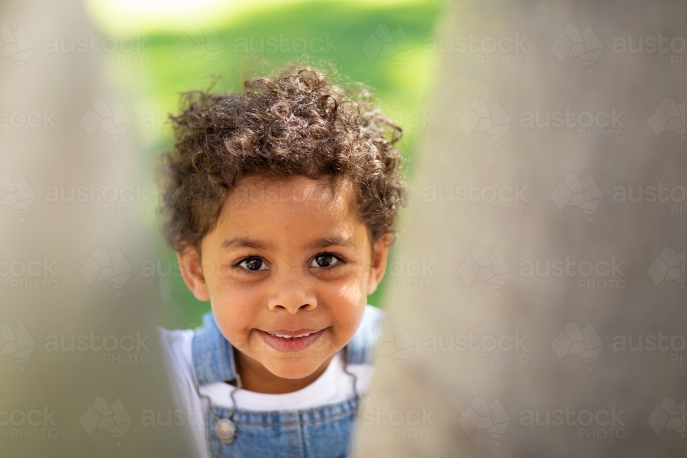 Image of smiling young child looking up through gap - Austockphoto