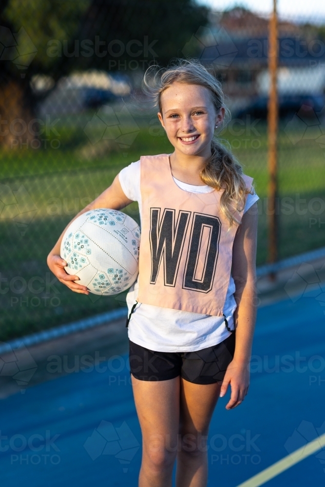 Image of smiling young girl holding netball and wearing WD wing defence ...
