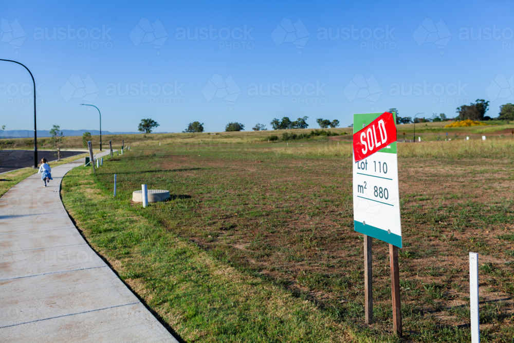 Image of sold sticker on for sale sign on empty lot in new housing ...