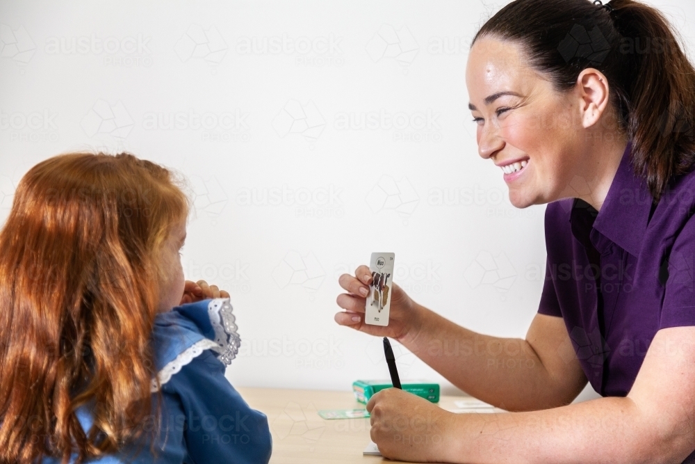 Image of Speech pathologist and child laughing together looking at ...