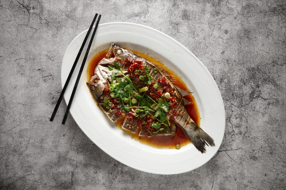 Image of Spicy steamed fish garnished with green onions. - Austockphoto