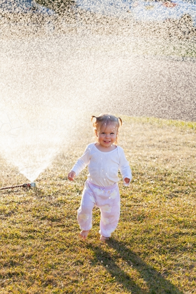 Image of springtime water play in front yard with child standing under ...