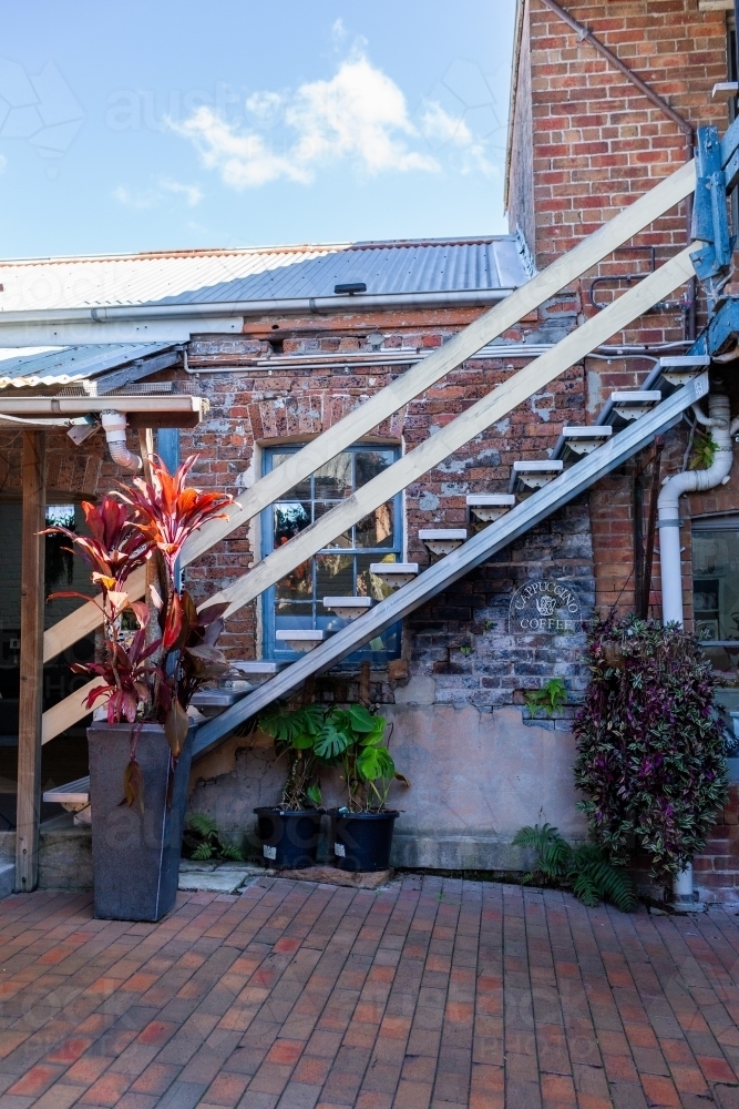 Image of Staircase outside of old building in alley with plants in pots ...