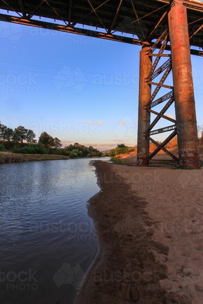 Image of Steel support pylons and bridge over country river - Austockphoto