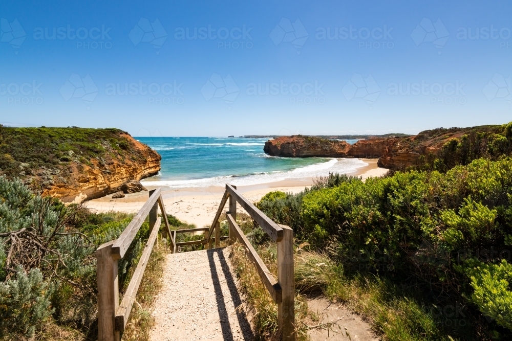 Image of Steps down to sandy cove with headlands. blue sky and blue sea ...