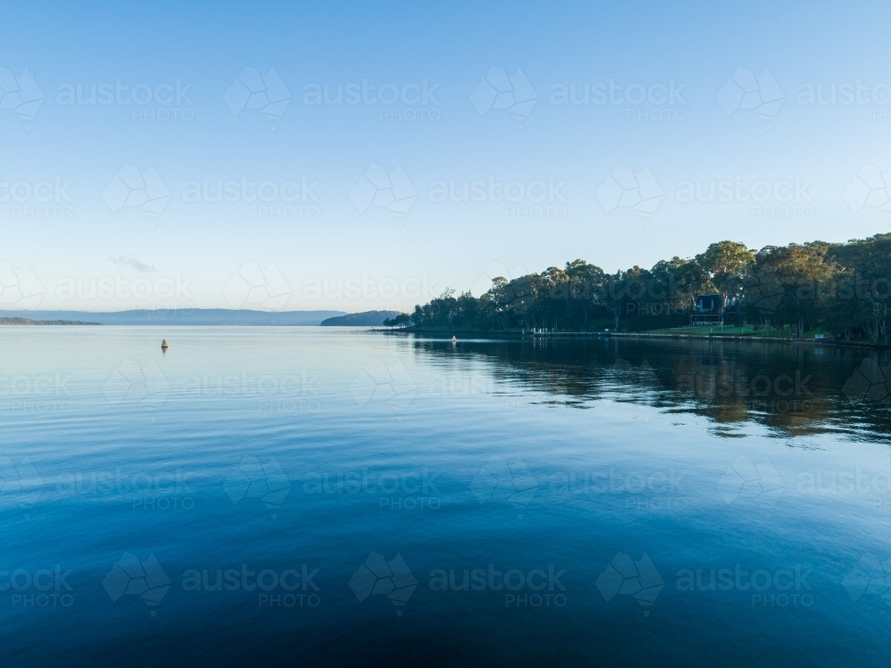 Image of Still blue waters of coastal lake with buoy in water ...