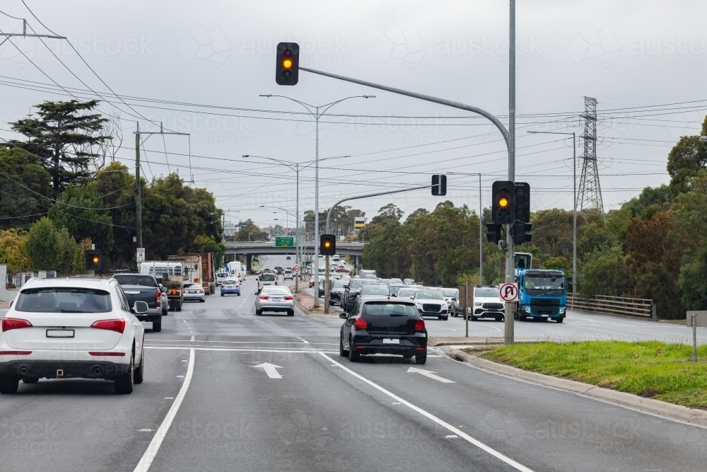 Image of Stopping at orange lights at intersection in city - Austockphoto