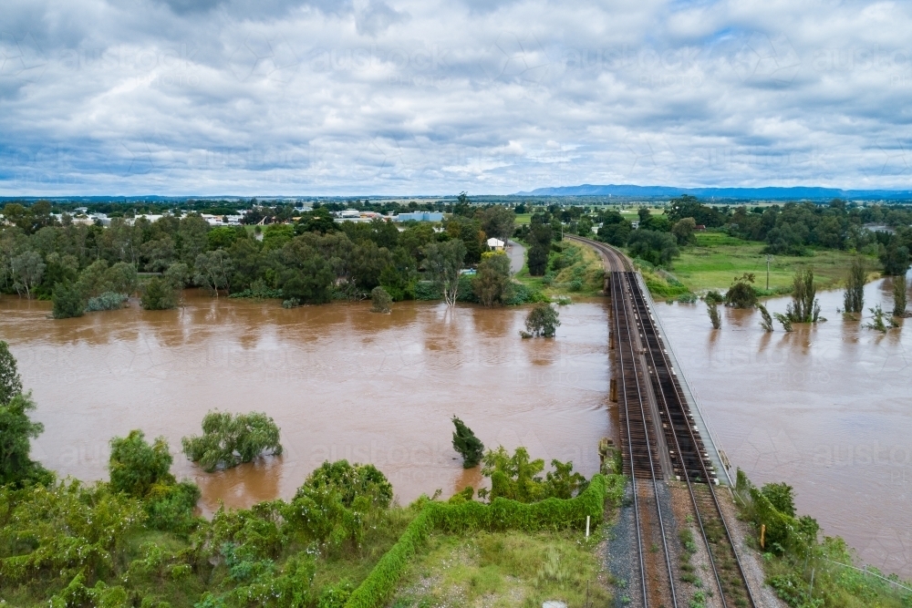 Image of Storm clouds above flooding river with train bridge over water ...