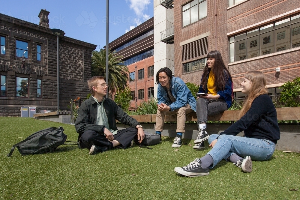 Image of students relaxing at university grounds - Austockphoto