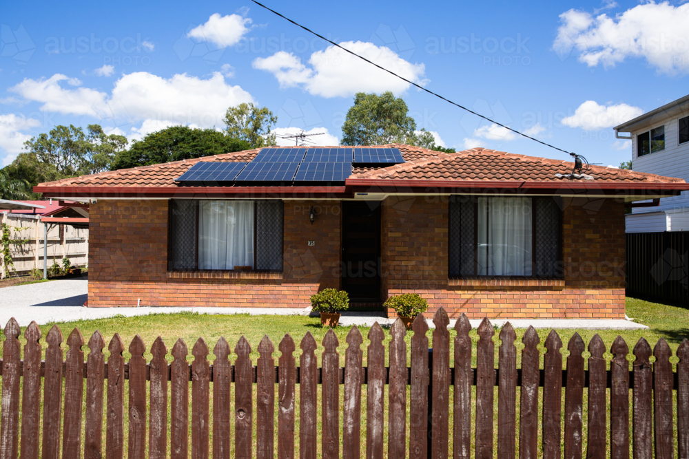 Image of suburban single storey brick home with solar panels - Austockphoto