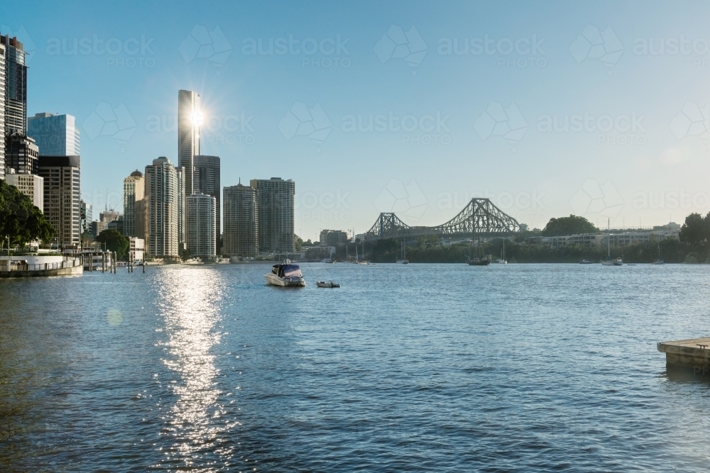 Image of sun reflecting off tall city building over water - Austockphoto