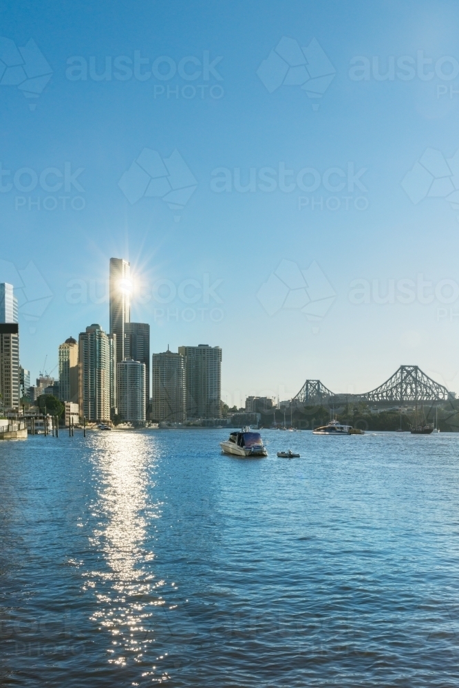 Image of sun reflecting off tall city building over water - Austockphoto
