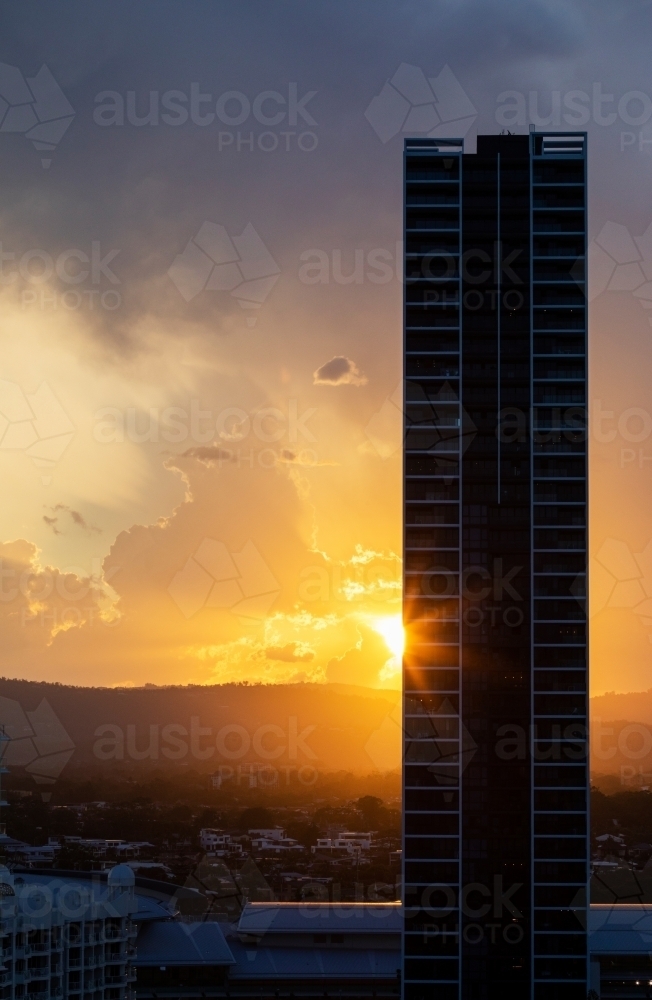 Image of sun setting behind high rise building - Austockphoto