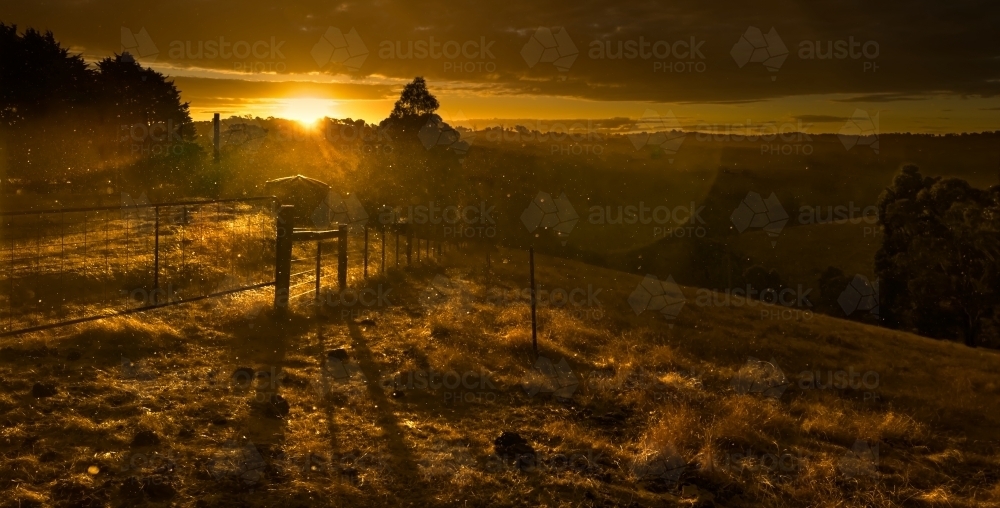 Image of Sun Setting Over Farmland with Light Rain Falling - Austockphoto