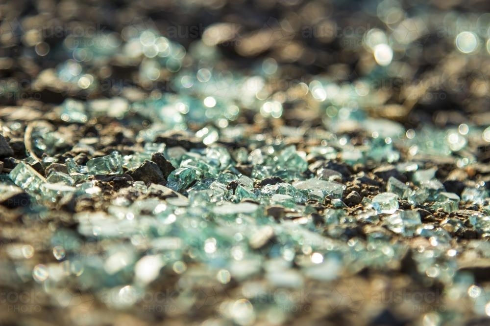 Image of Sun shining off broken glass in gravel - Austockphoto