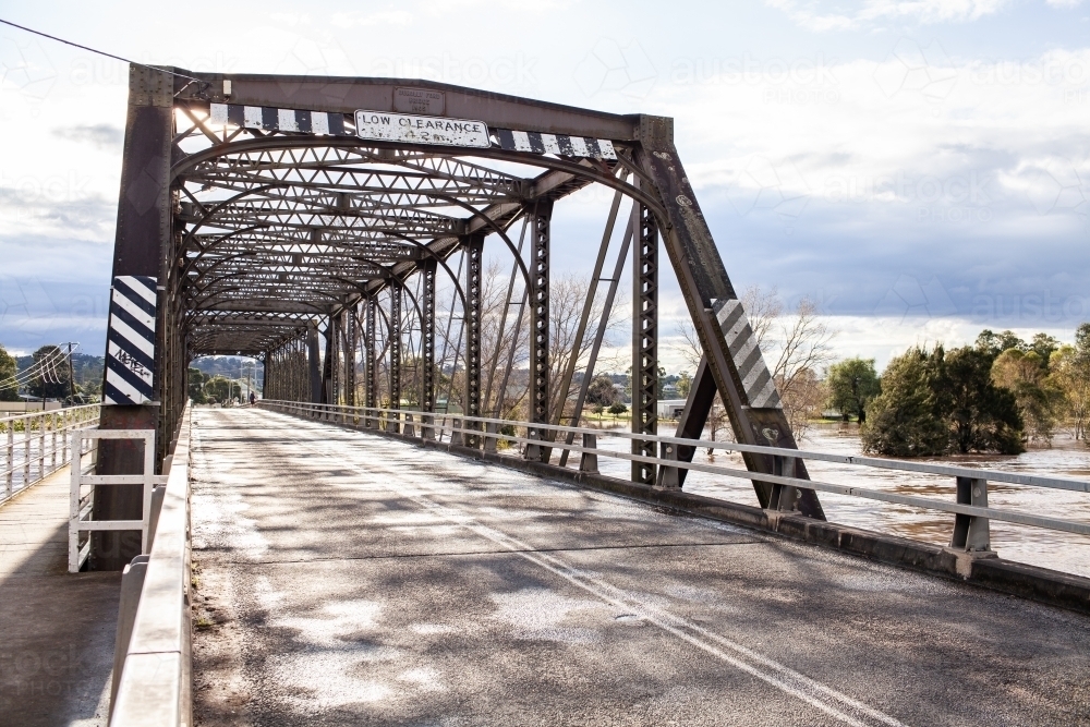Image of Sunlight over old truss bridge in Singleton with floodwaters ...