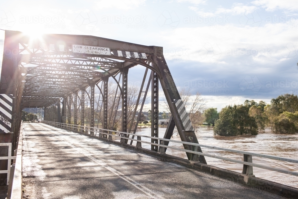 Image of Sunlight over old truss bridge in Singleton with floodwaters ...