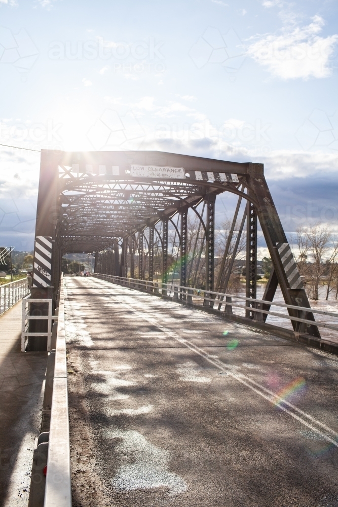 Image of Sunlight over old truss bridge in Singleton with floodwaters ...