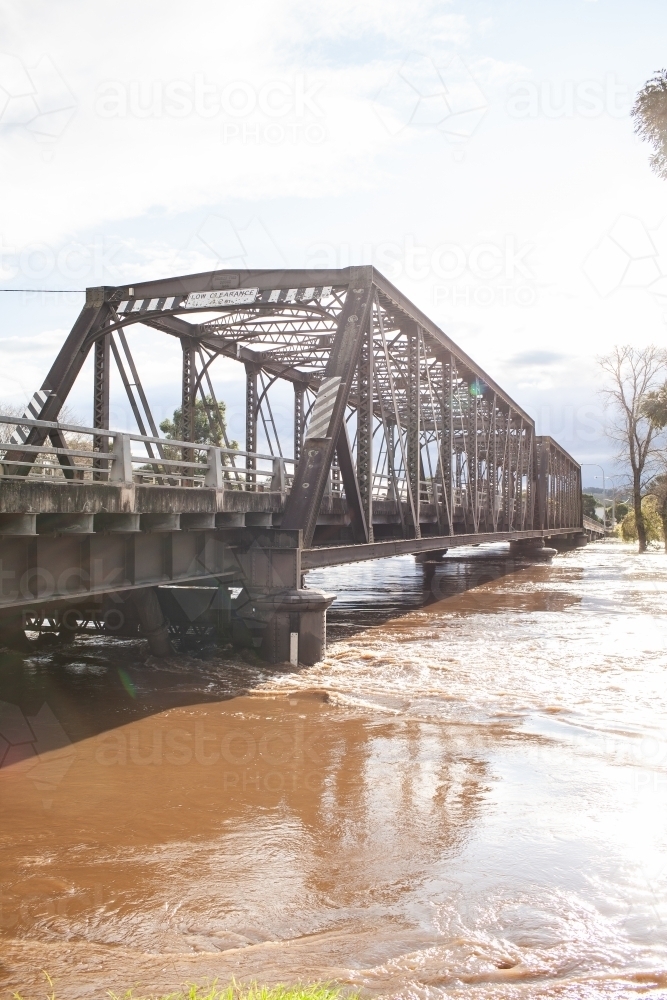 Image of Sunlight over old truss bridge in Singleton with floodwaters ...
