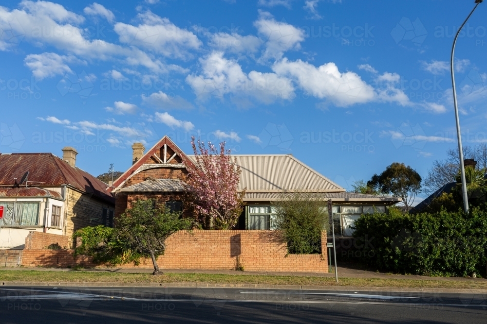 Image of Sunlit house with brick fence around garden along street in ...
