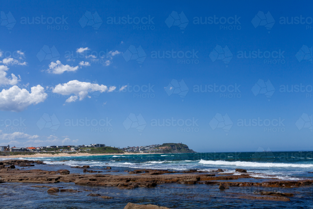 Image of Sunlit seaside scene of rocks and blue ocean waters with ...
