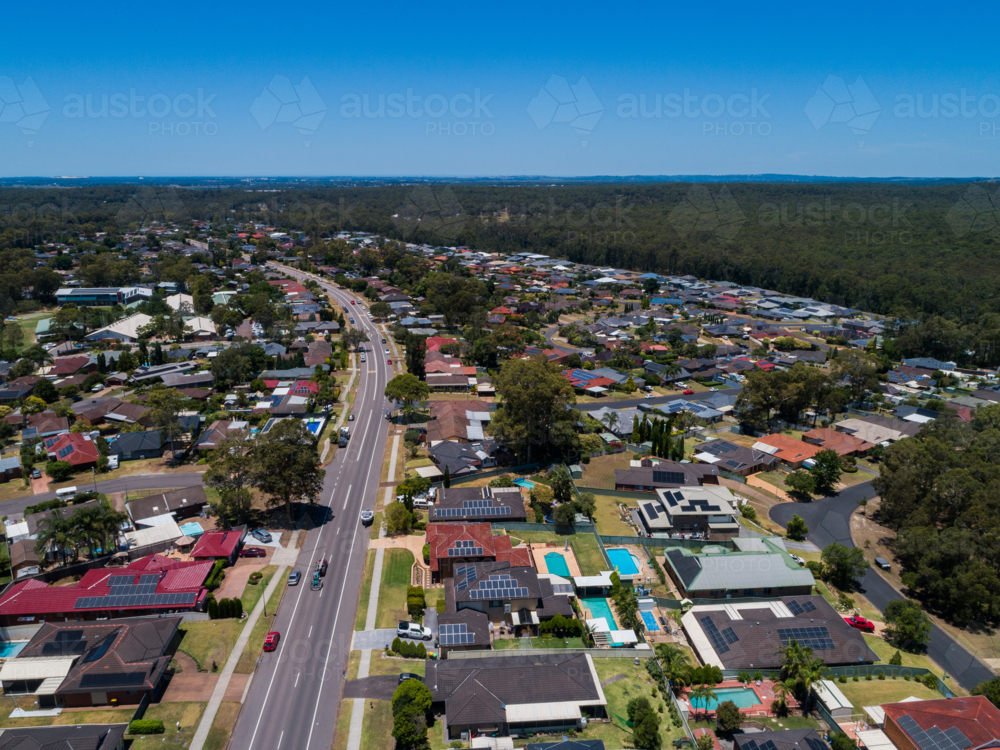 Image of Sunlit street in suburbs with houses alongside road in ...