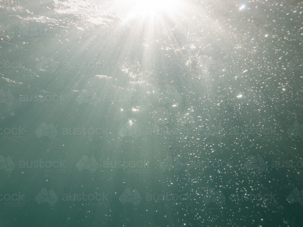 Image of Sunrays underwater with sparkling bubbles in blue pool water - Austockphoto