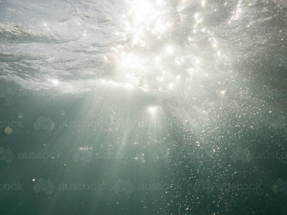 Image of Sunrays underwater with sparkling bubbles in blue pool water - Austockphoto