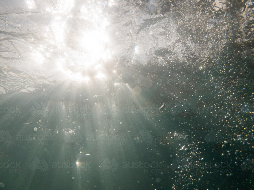 Image of Sunrays underwater with sparkling bubbles in blue pool water - Austockphoto