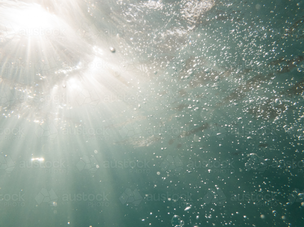 Image of Sunrays underwater with sparkling bubbles in blue pool water - Austockphoto